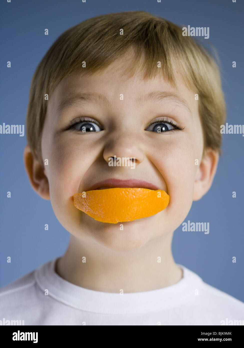 Closeup of boy eating orange wedge Stock Photo - Alamy
