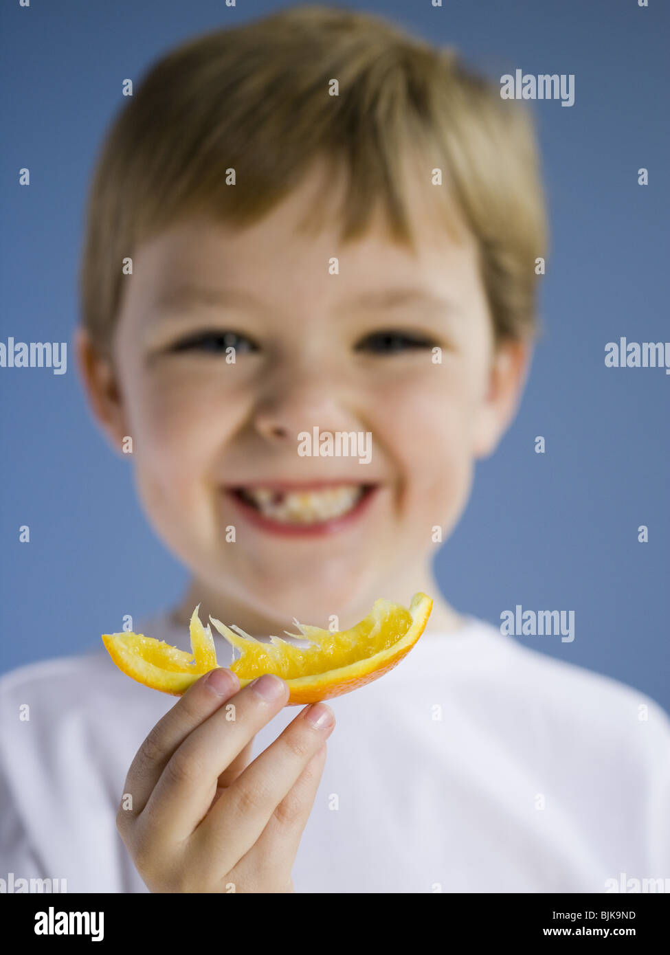 Closeup of boy eating orange wedge Stock Photo - Alamy