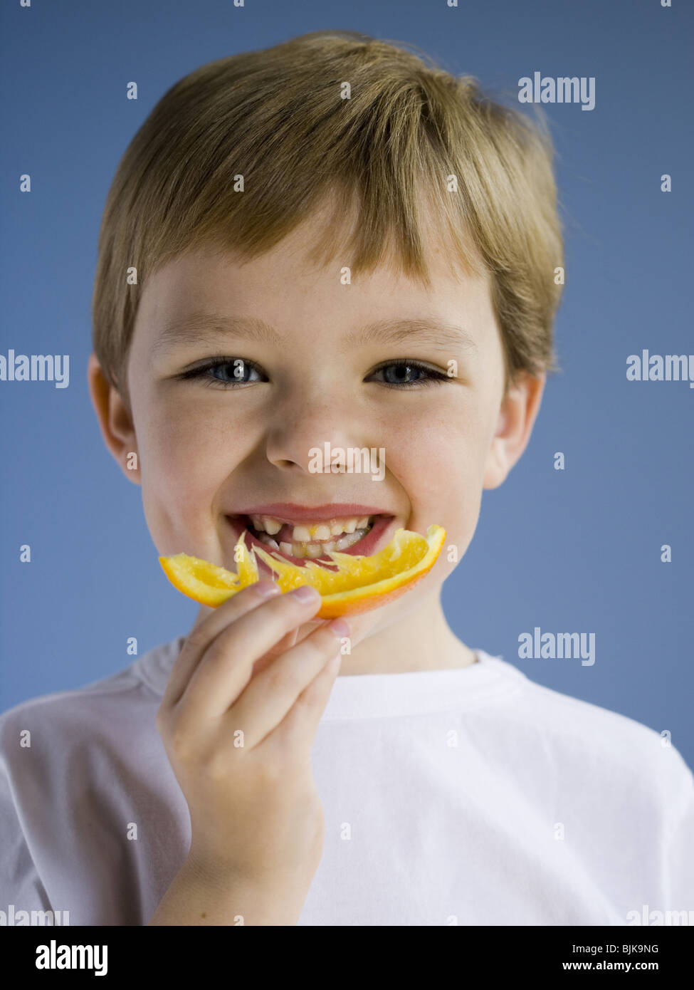 Closeup of boy eating orange wedge Stock Photo - Alamy