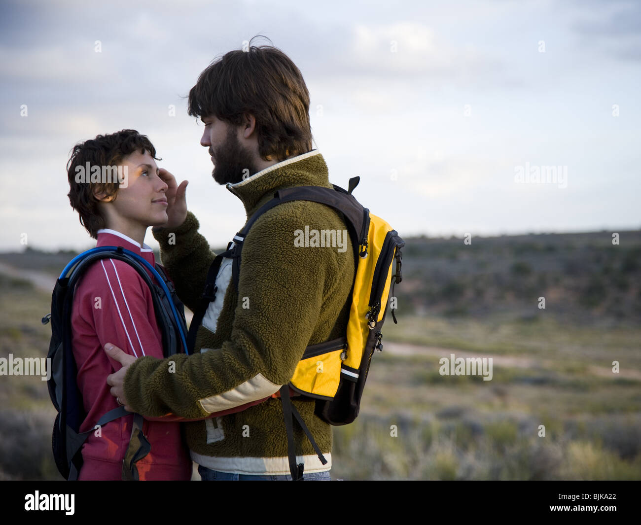 Man and woman with backpacks embracing outdoors Stock Photo - Alamy