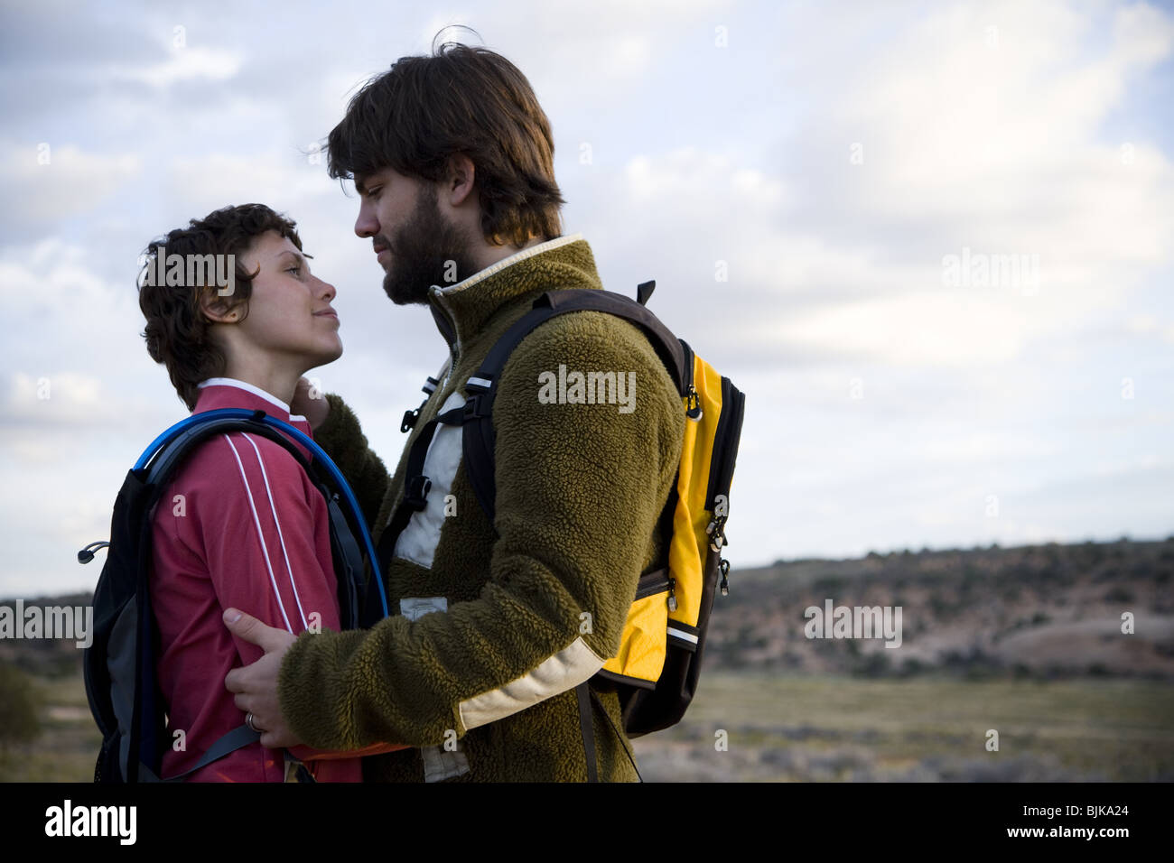 Man and woman with backpacks embracing outdoors Stock Photo - Alamy
