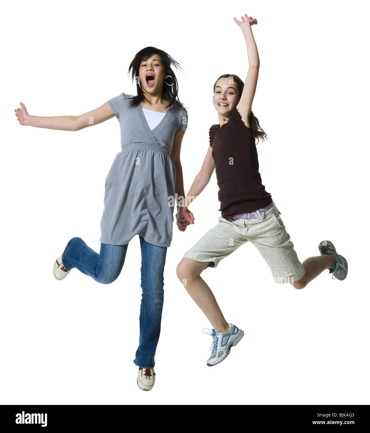Two girls jumping and smiling Stock Photo - Alamy