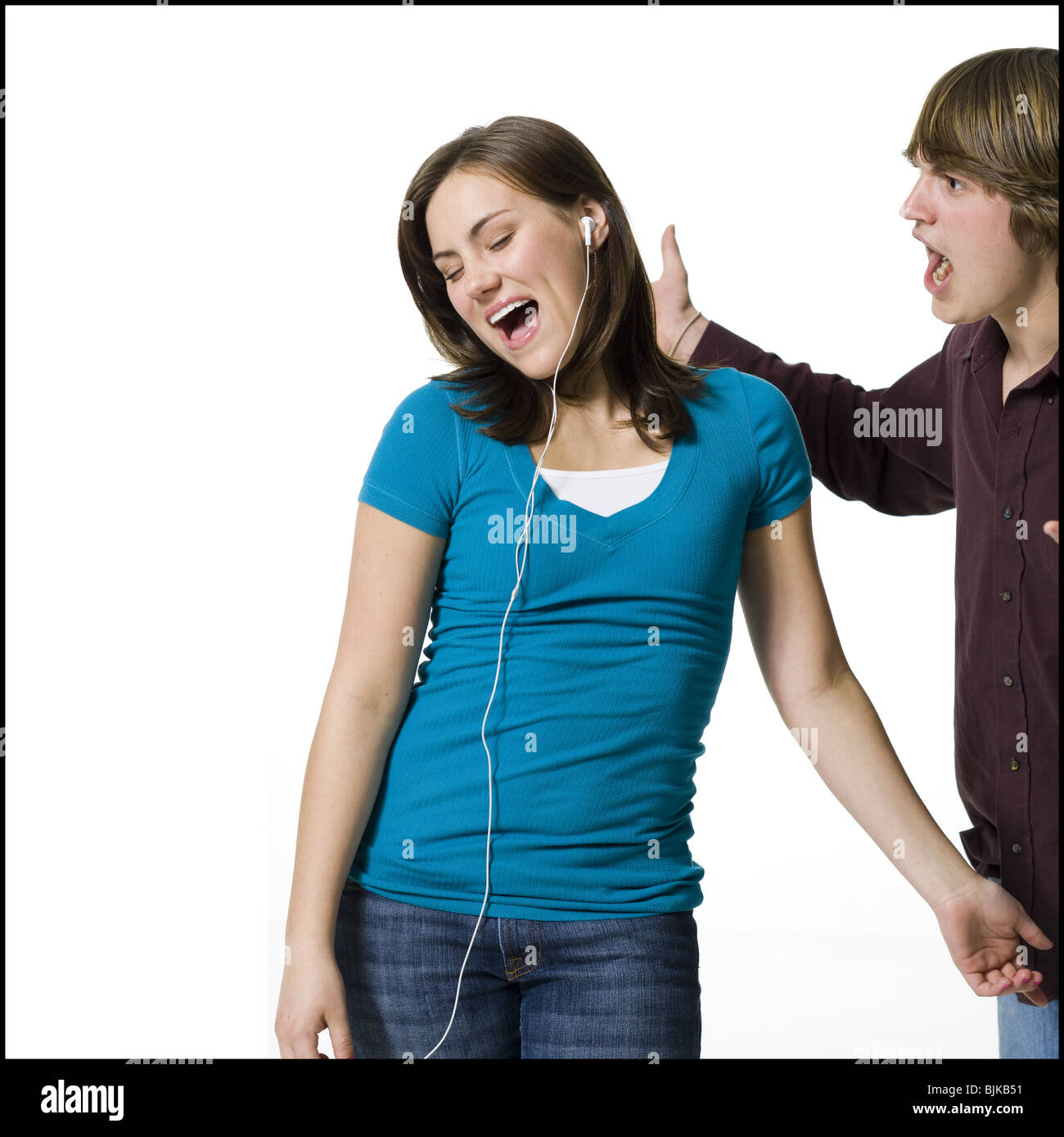 Girl listening to mp3 player with boy yelling Stock Photo - Alamy