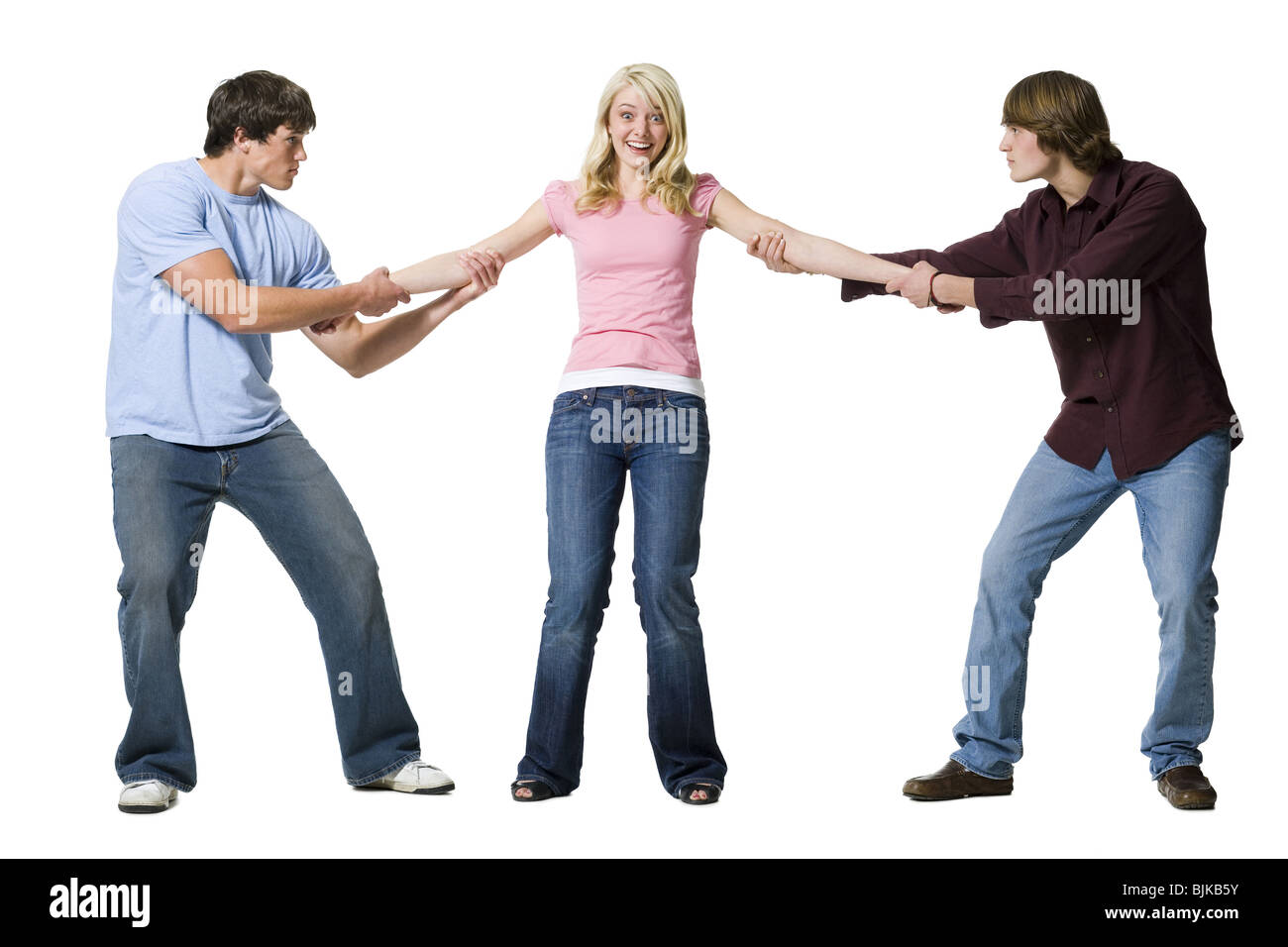 Two boys tugging at arms of girl Stock Photo - Alamy