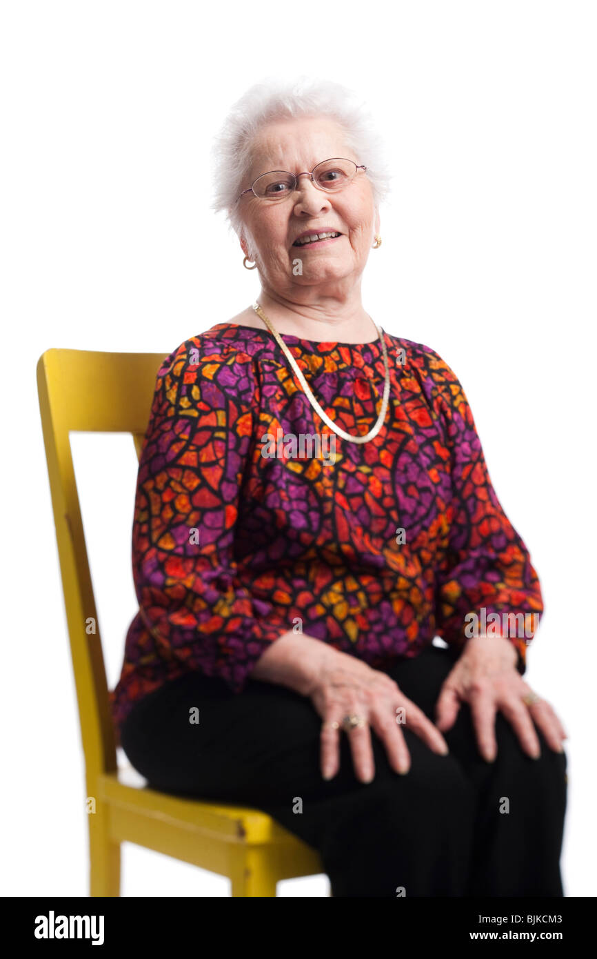 Elderly woman sitting in yellow chair Stock Photo - Alamy
