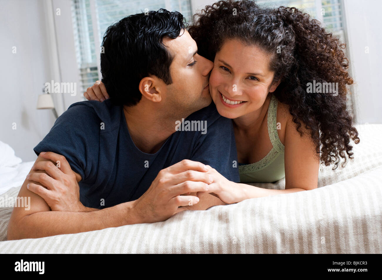 Man and woman on bed snuggling Stock Photo - Alamy