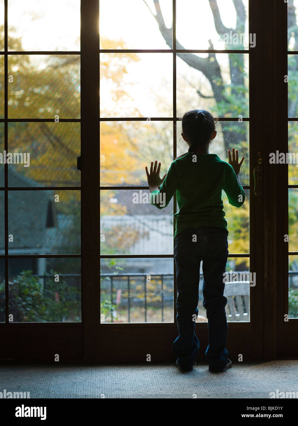 Young girl looking through large window Stock Photo - Alamy
