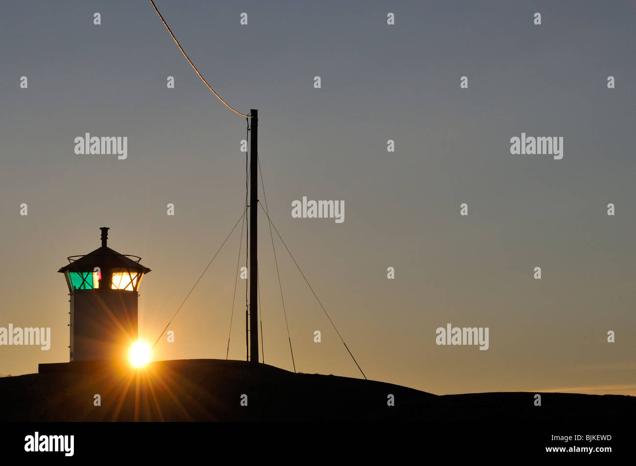 Sun Setting Behind a Lighthouse Stock Photo - Alamy