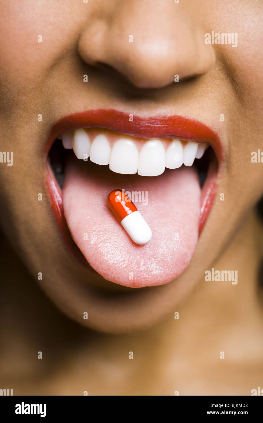 Woman wearing red lipstick with a pill on tongue Stock Photo - Alamy