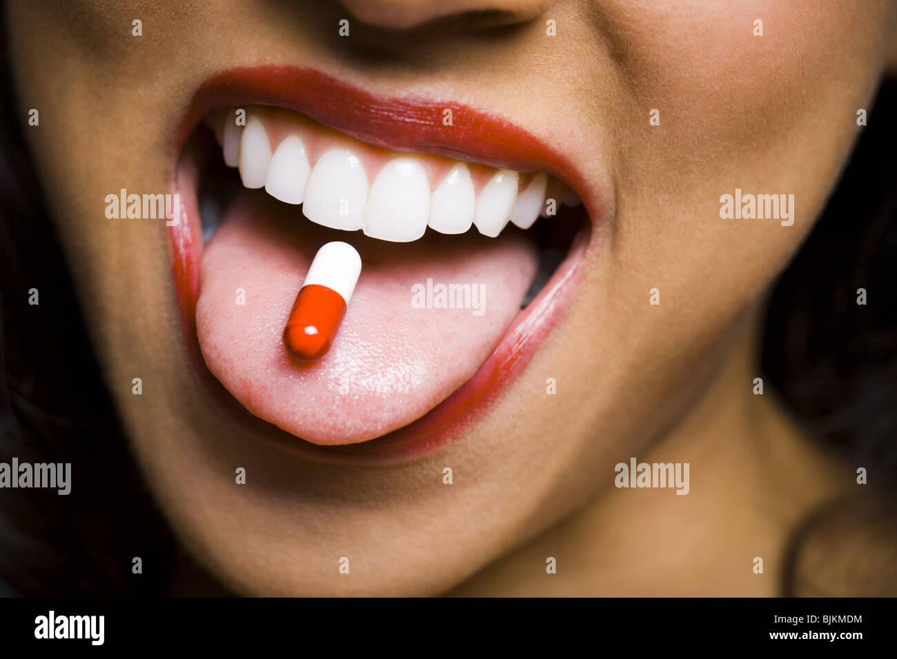 Woman wearing red lipstick with a pill on tongue Stock Photo - Alamy