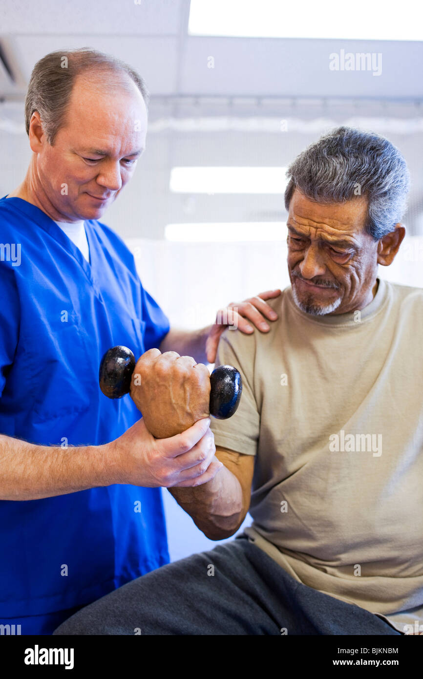 Physical Therapist assisting a man with weights Stock Photo - Alamy