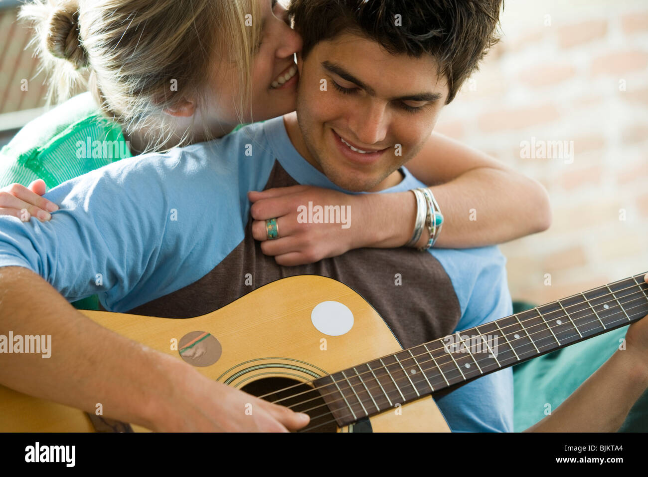 Man playing guitar with woman behind him Stock Photo - Alamy