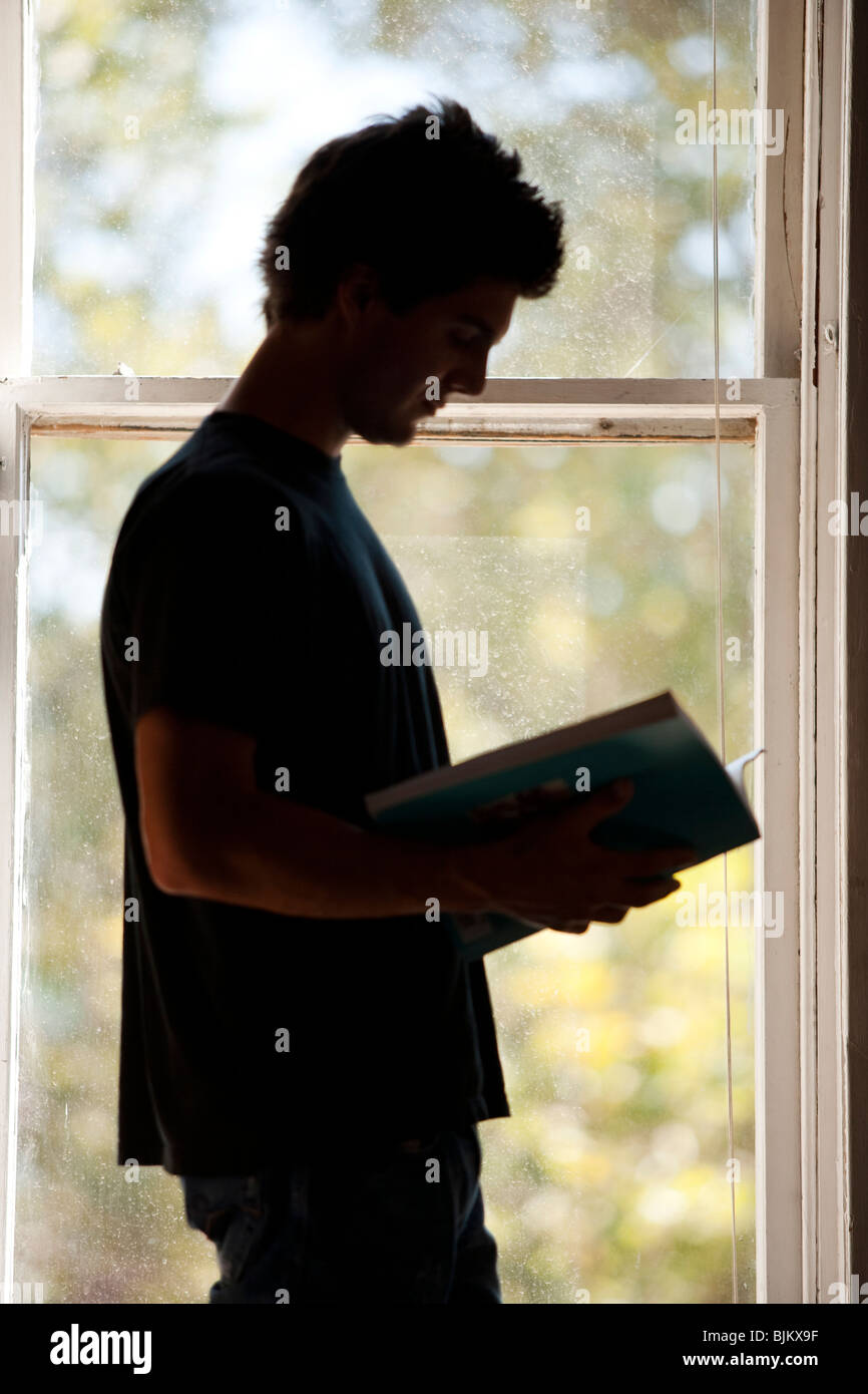 Man standing at window reading Stock Photo - Alamy