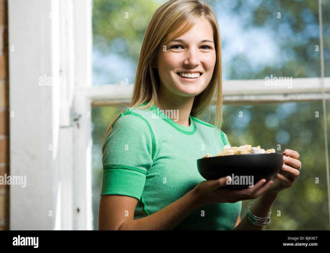 Woman in front of window eating bowl of cereal Stock Photo - Alamy