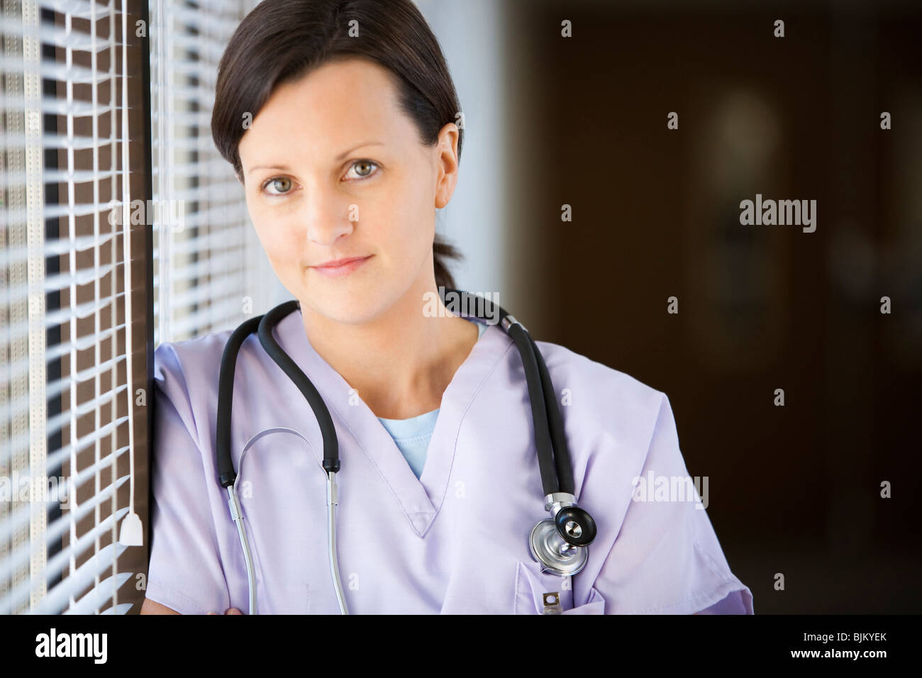 Female nurse leaning on blinds Stock Photo - Alamy