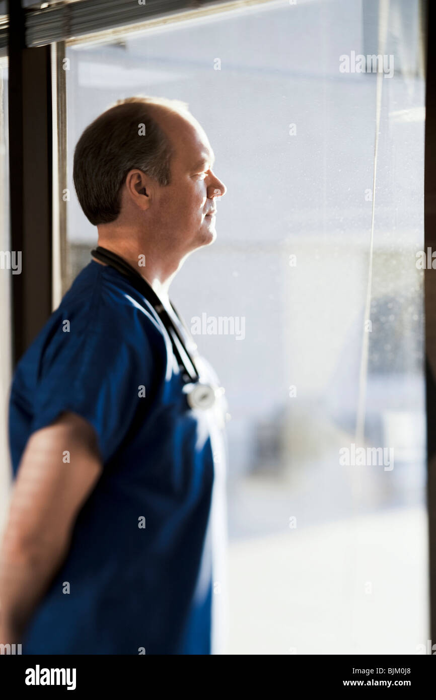 Male doctor looking through window Stock Photo - Alamy