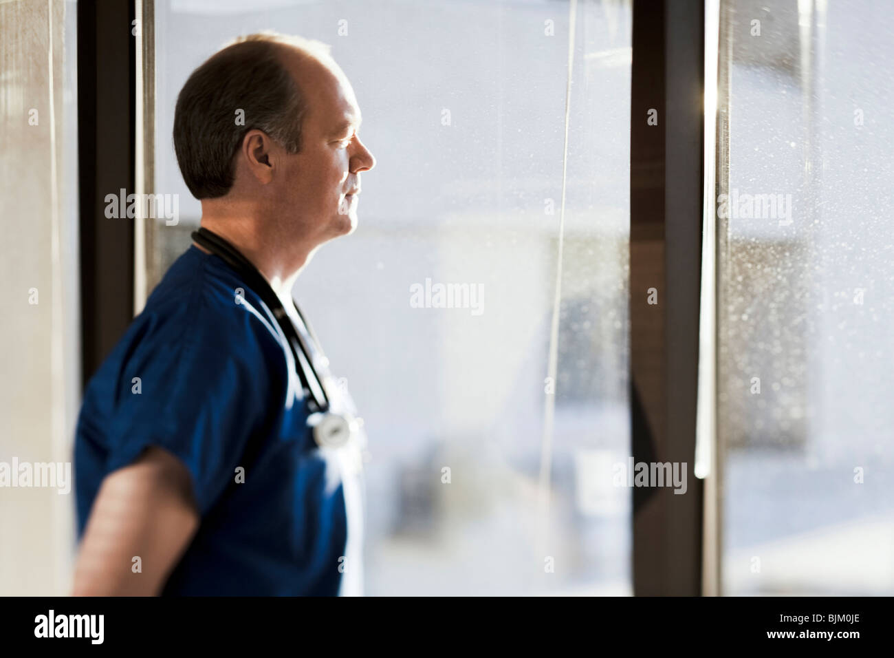 Male doctor looking through window Stock Photo - Alamy
