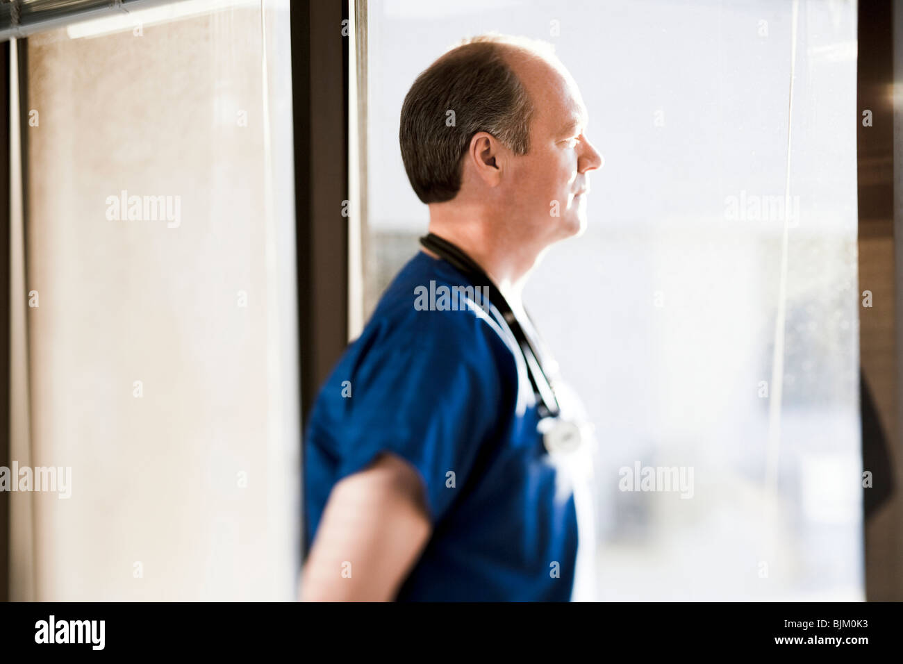 Male doctor looking through window Stock Photo - Alamy