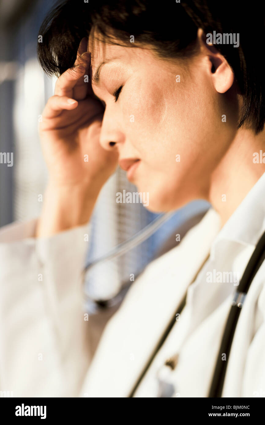 Female Doctor with hand on head Stock Photo - Alamy