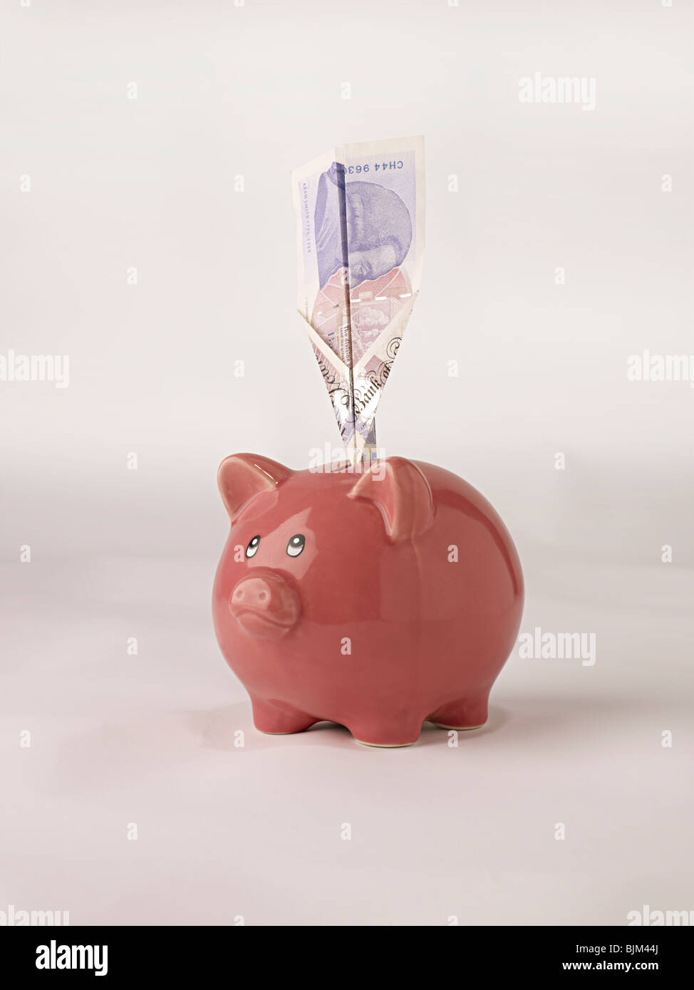 twenty pound note paper dart in a pink piggy bank Stock Photo - Alamy