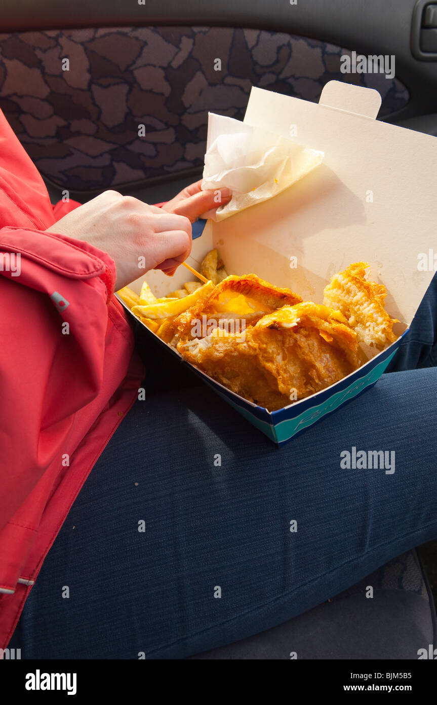 A MODEL RELEASED picture of a woman eating fish & chips in a car in the ...