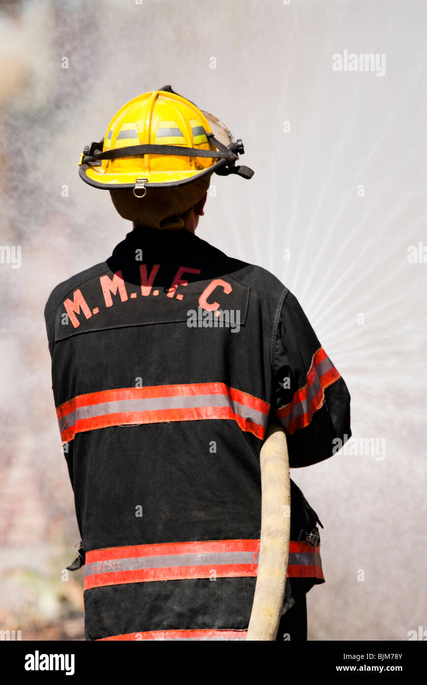 Rear View of a firefighter with hose Stock Photo - Alamy