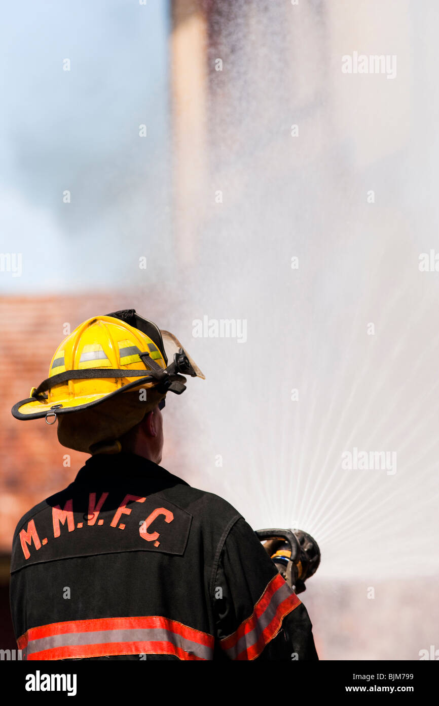 Rear View of a firefighter with hose Stock Photo - Alamy