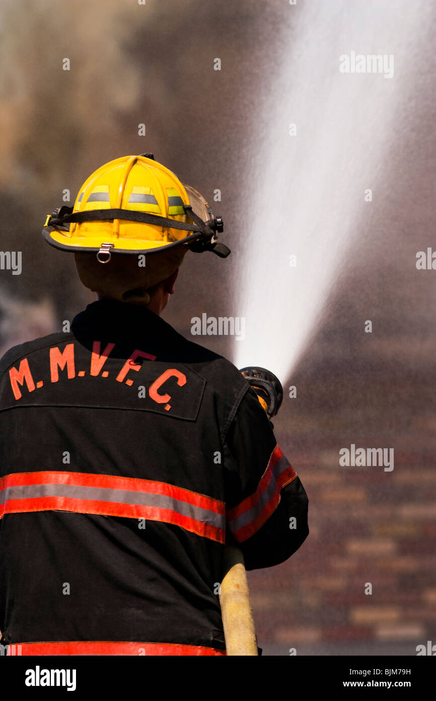 Rear View of a firefighter with hose Stock Photo - Alamy