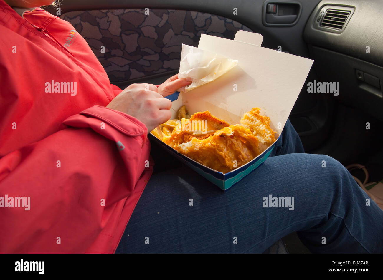 A MODEL RELEASED picture of a woman eating fish & chips in a car in the ...