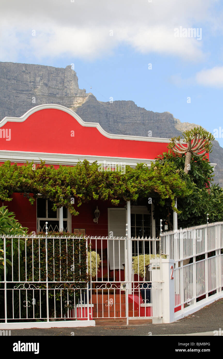 Red & white painted house with secure metal fencing and a backdrop of ...