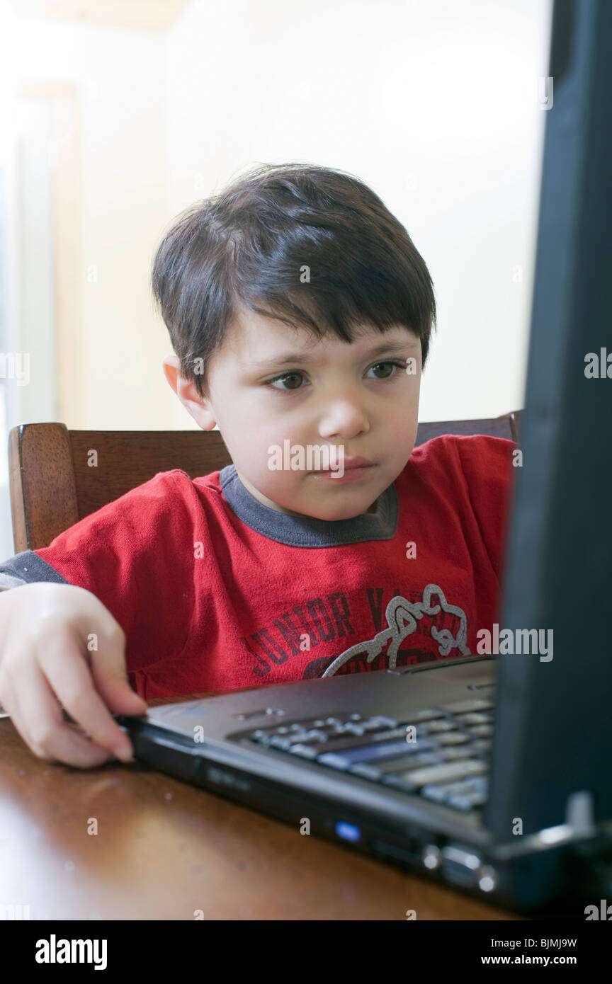 Four and 1/2 year old Hispanic boy surfs the internet on his laptop at ...