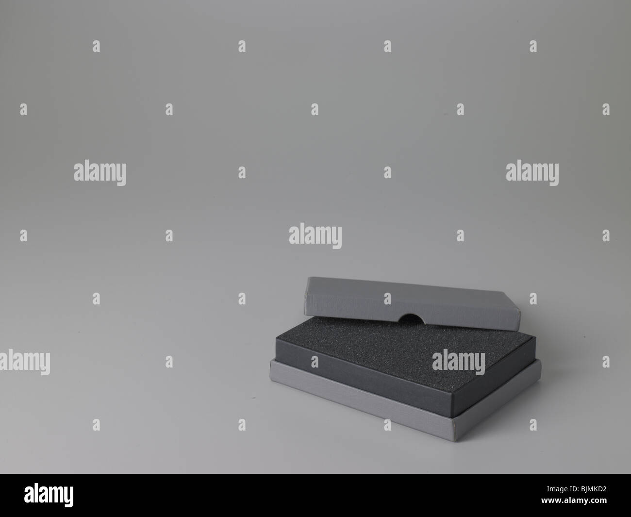 Grey box on grey background with lid to the left Stock Photo - Alamy