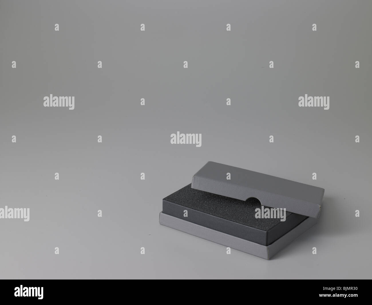 Grey box on grey background with lid half way on Stock Photo - Alamy