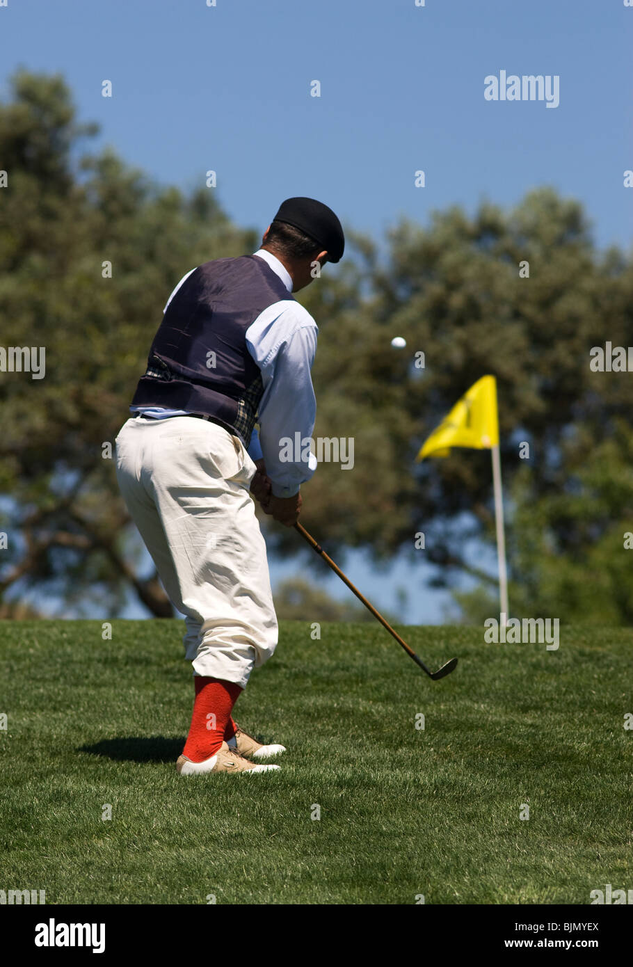 A golfer playing the game with a hickory golf club and dressed in early ...