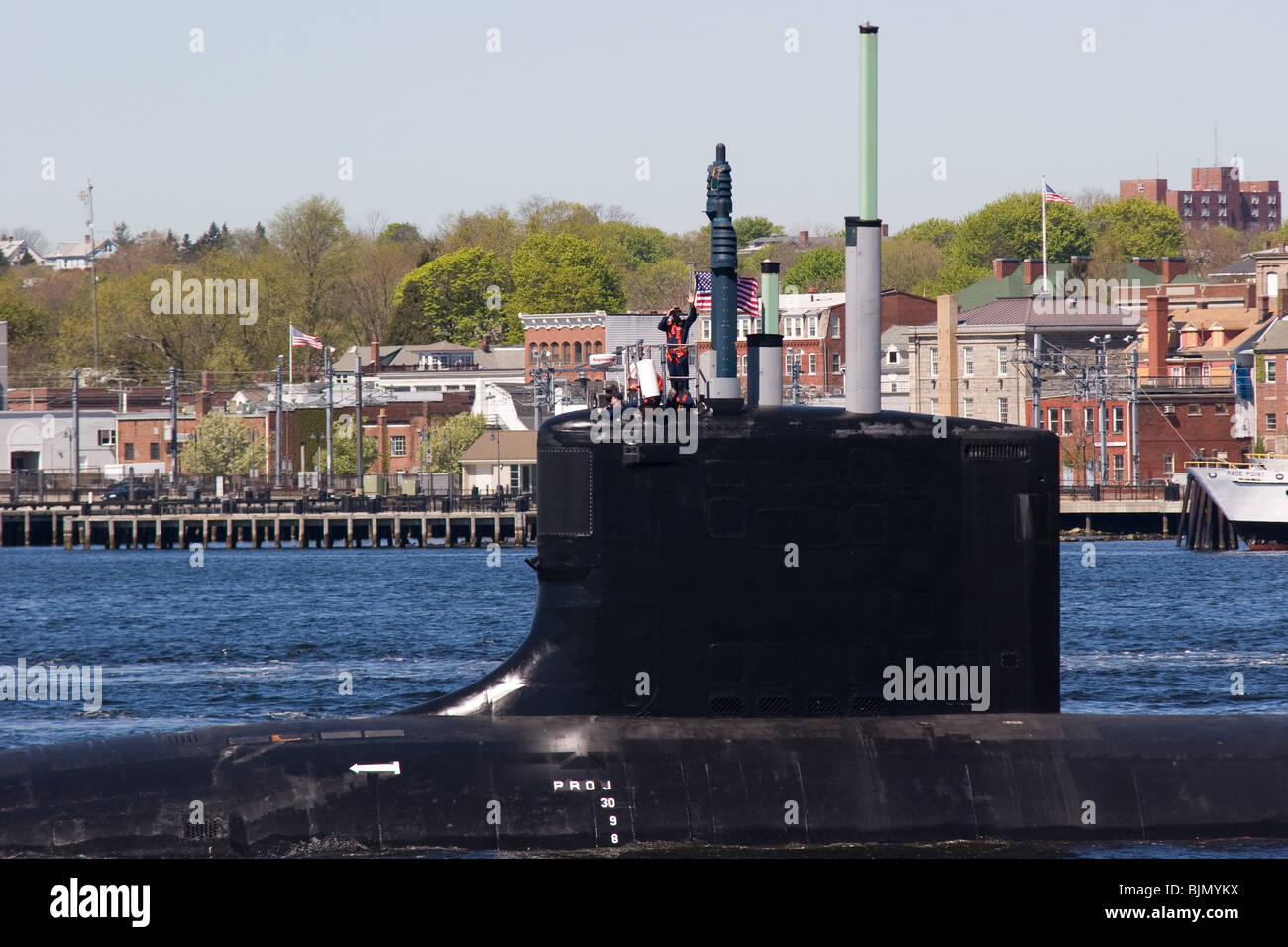 A US Navy Virginia class submarine crew member waves to shore along the ...