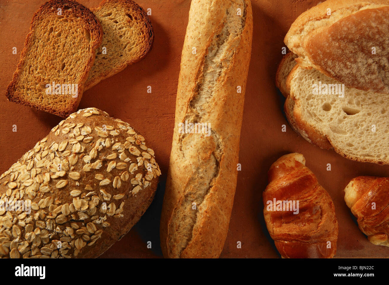 Varied bread styles still over warm clay background Stock Photo - Alamy