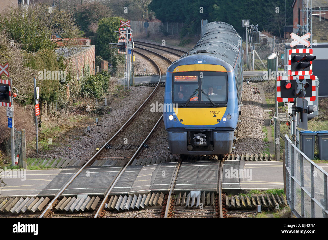 Passenger train approaching an 'open level crossing' Stock Photo - Alamy