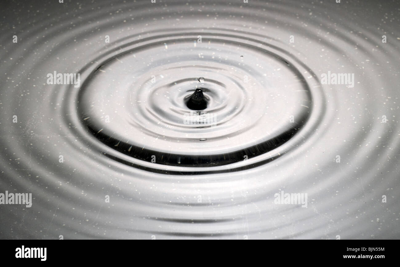 A droplet of water falling into a puddle and creating ripples Stock ...