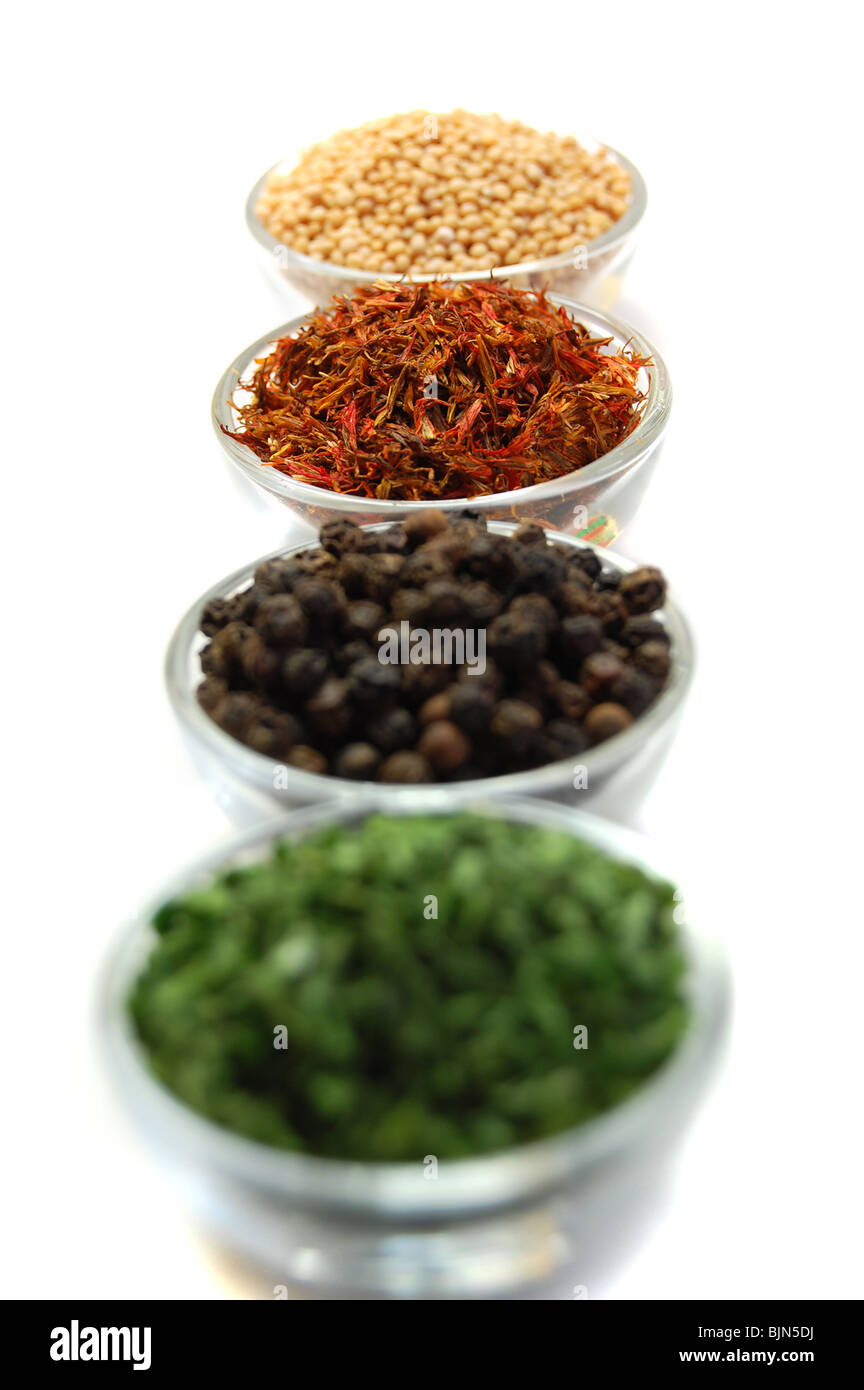 Four small glass containers filled with dry spices; saffron, mustard ...