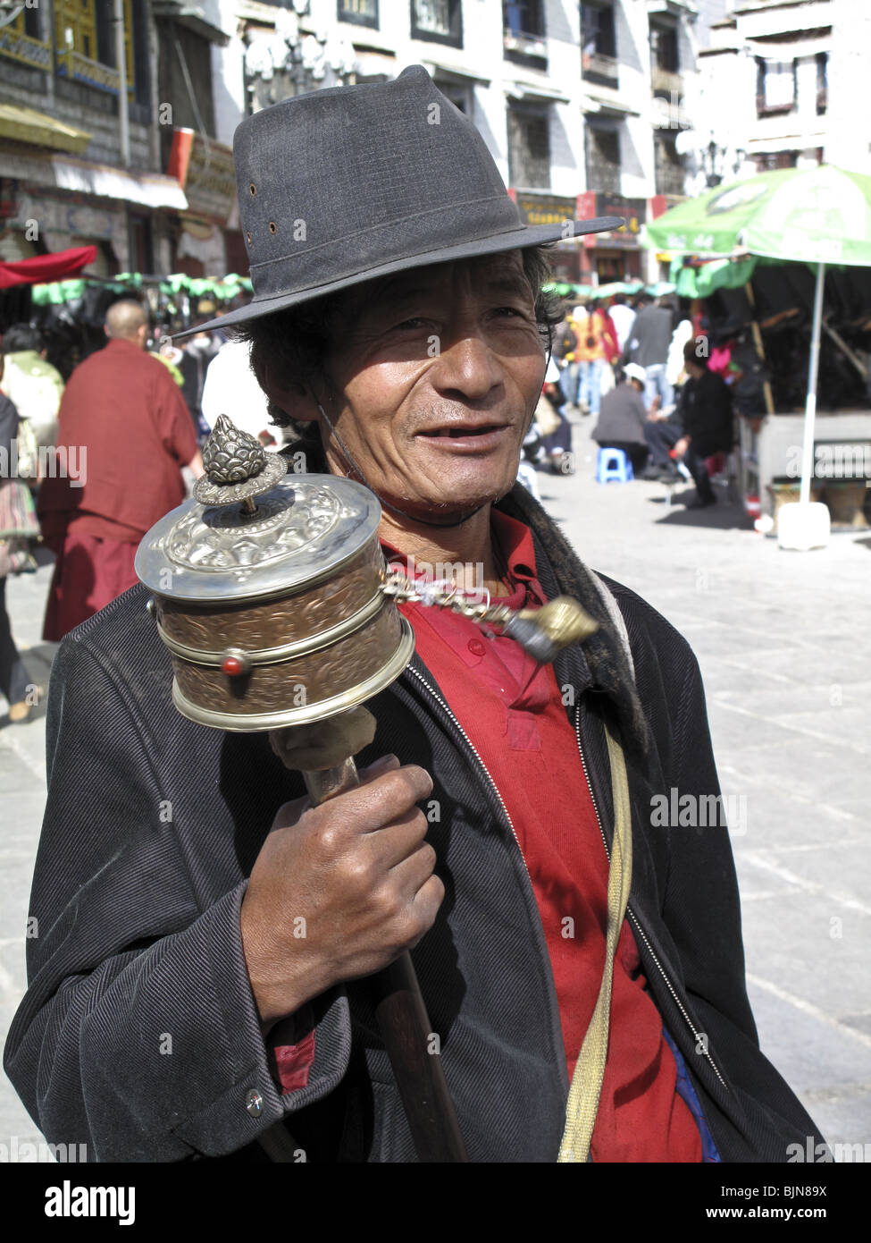Male pilgrim swinging personal prayer wheel in Barkhor Square, Lhasa ...
