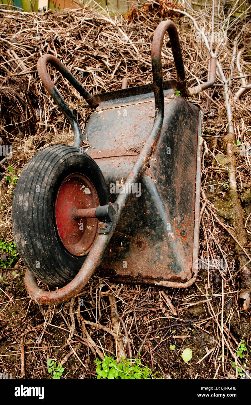 Rusty wheelbarrow on pile of branches Stock Photo - Alamy