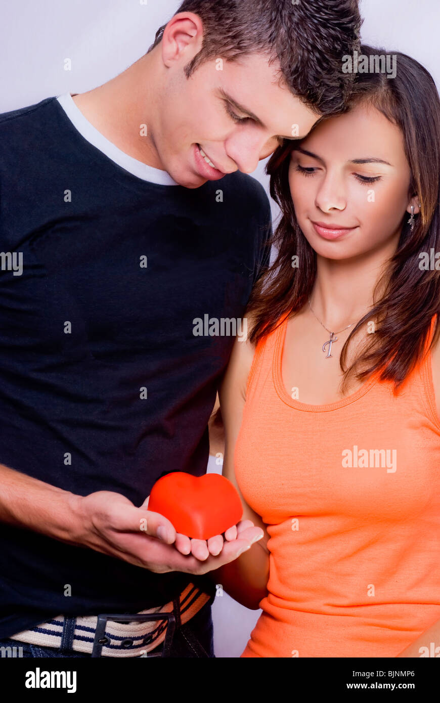 Young couple holding together a heart symbolizing a love relation ...
