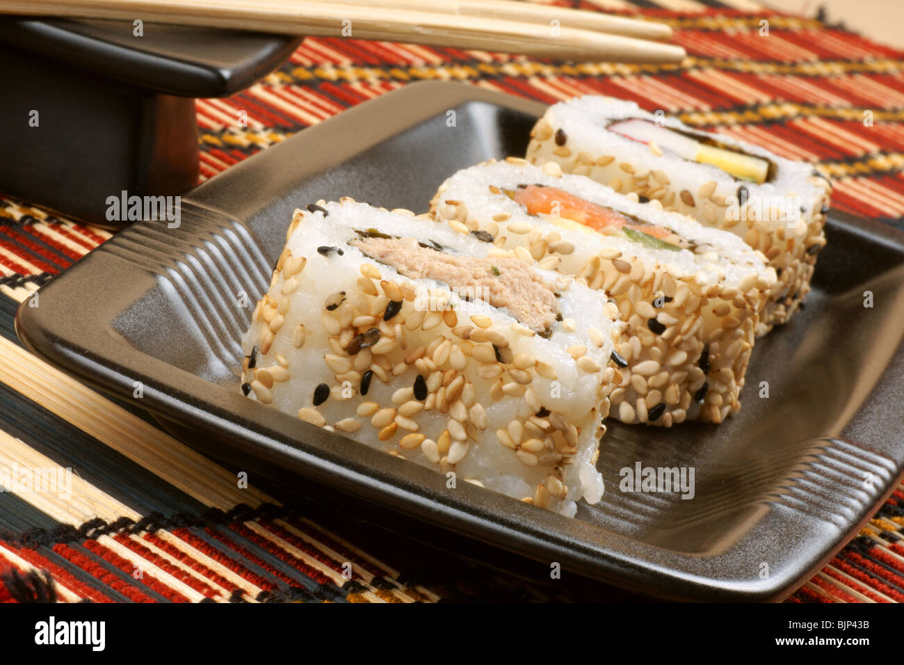 Assorted japanese maki sushi on a black tray with chopsticks, ready to ...