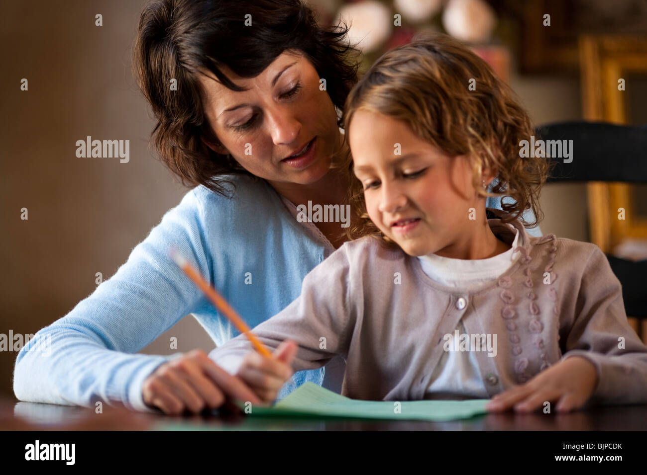 Mother helping daughter write Stock Photo - Alamy