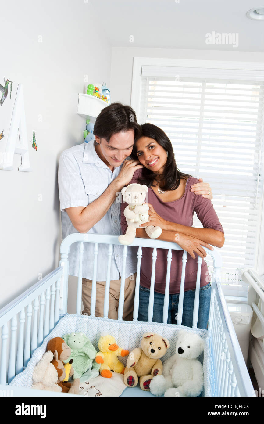 Married couple leaning on baby crib Stock Photo - Alamy