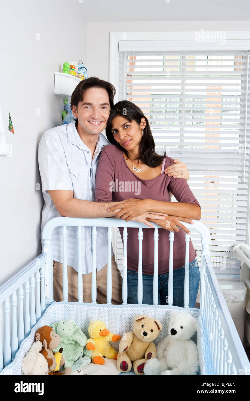 Married couple leaning on baby crib Stock Photo - Alamy
