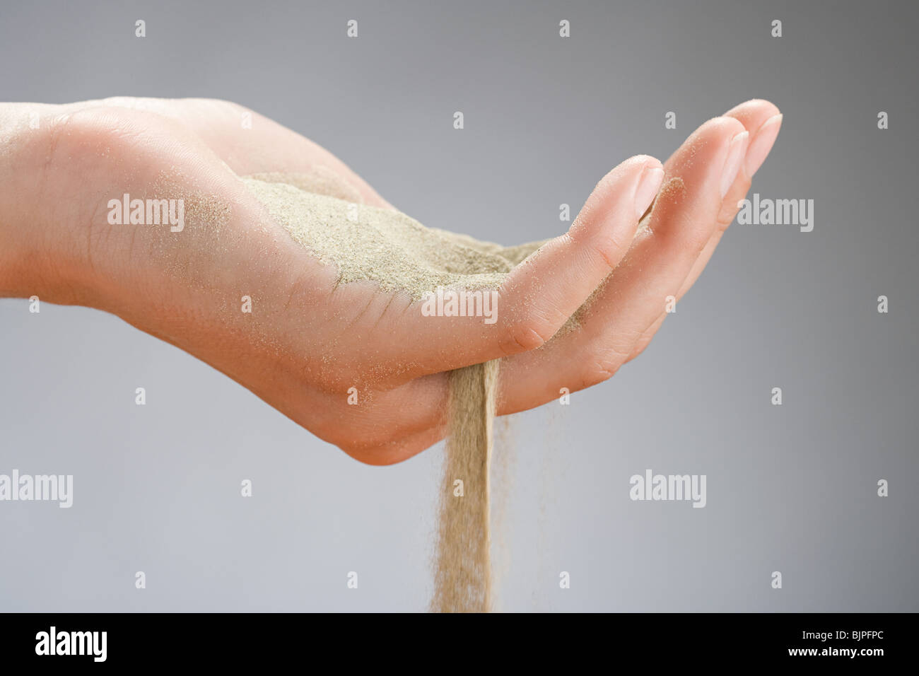 Sand falling through a womans hand Stock Photo - Alamy