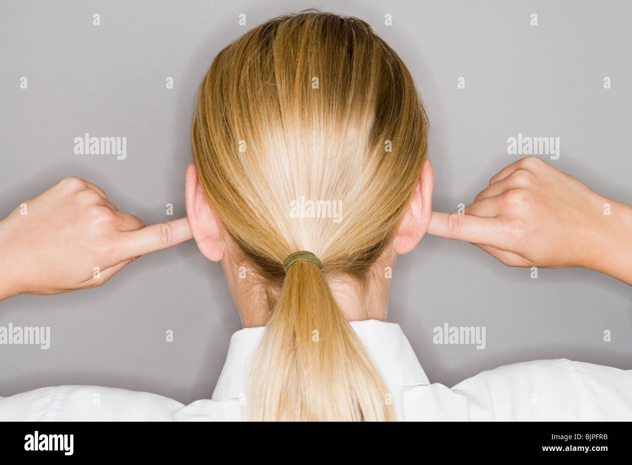 A woman with her fingers in her ear Stock Photo - Alamy