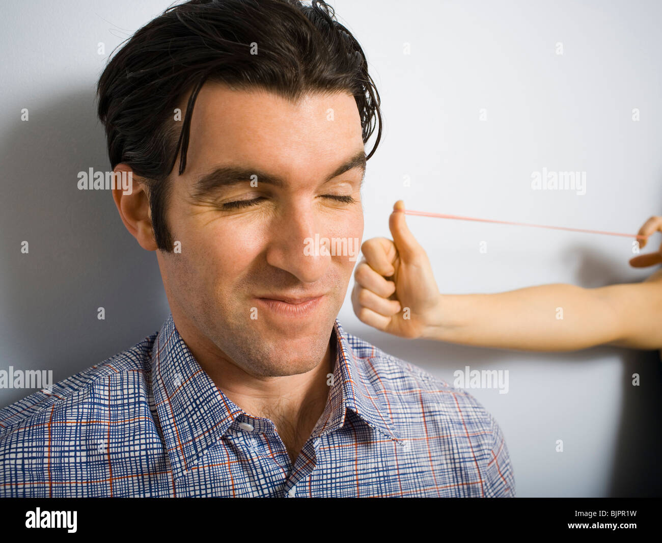 Man almost getting hit with rubber band Stock Photo - Alamy