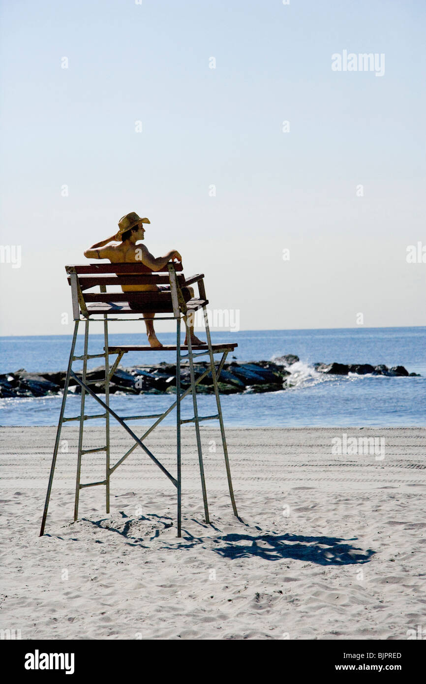 Man sitting in lifeguard chair at beach Stock Photo - Alamy